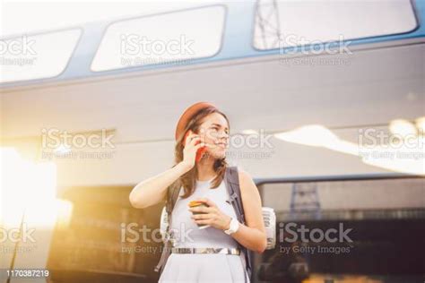 테마 관광 및 여행 젊은 학생 손에 배낭과 컵 커피와 기차 근처 기차역에 서 드레스와 모자에 아름다운 젊은 백인 소녀 스마트폰 기술 사용 관광에 대한 스톡 사진 및 기타