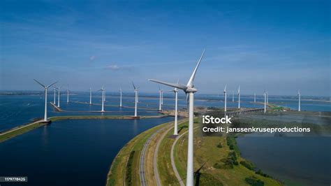 네덜란드의 일부 흐림과 푸른 하늘 아래 벨루베미어 해안을 따라 두 개의 블레이드와 세 개의 블레이드가있는 풍력 터빈으로 구성된 현대적인 풍력 발전 단지 개발에 대한 스톡