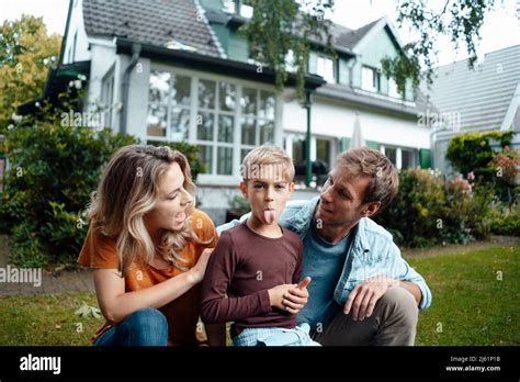 Mother And Father Looking At Son Sticking Out Tongue At Backyard Stock Photo Alamy