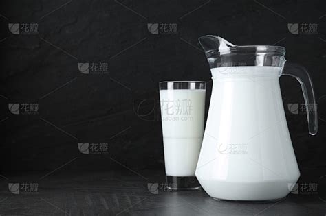 黑色的桌子上放有新鲜牛奶的水罐和玻璃杯空间的文本