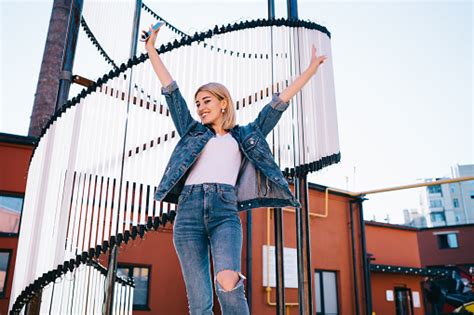 스마트 폰 기술을 들고 카메라를 비웃는 손을 들고 행복한 힙스터 소녀의 절반 길이 초상화 청바지 의류를 입은 쾌활한 백인 여성이