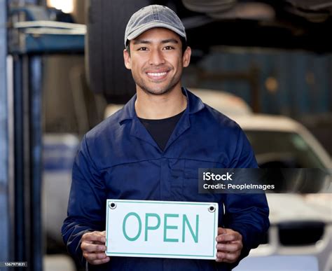 작업장에 서있는 동안 열린 표지판을 들고 있는 잘생긴 젊은 남성 정비사의 자른 초상화 20 29세에 대한 스톡 사진 및 기타 이미지 20 29세 30 34세 갈색