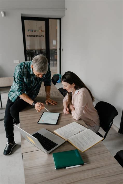 Teacher Assisting A Student During A Lesson In A Modern Classroom Stock