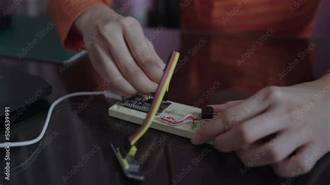 Close Up Hand Of Woman Plugging A Pin On An Electronic Circuit Board With An Arduino