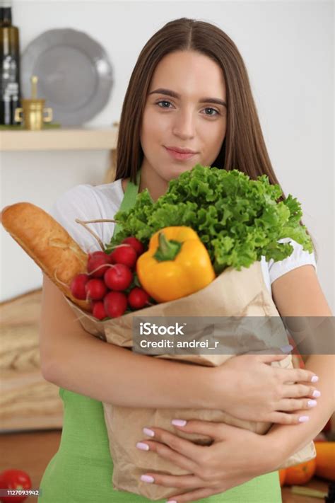 부엌에서 요리 하는 젊은 여자 야채와 과일의 전체 종이 가방을 들고 소녀 Householding 맛 있는 음식과 채식주의 라이프 스타일 개념 가정 생활에 대한 스톡 사진 및