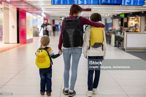 두 자녀를 둔 어머니는 출발 게이트 근처의 공항 환승 홀에서 비행기를 타고 탑승을 기다리고 있습니다 아이들과 함께 공기로 활동적인 가족 라이프 스타일 여행 가정 생활에 대한