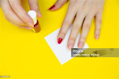 여자는 노란색 배경에 빨간색 매니큐어를 적용합니다 N소녀 만들기 매니큐어 집에서 살롱 절차 아름다운 손과 손톱 클로즈업 매크로 사진 화려하고 창조적인 개념에 대한 스톡 사진