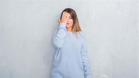 젊은 성인 여자 얼굴과 놀라운 감정에 겨울 옷 커버 자신감 미소와 함께 손으로 한쪽 눈을 입고 회색 그런 지 벽에 가리기에 대한 스톡 사진 및 기타 이미지 Istock