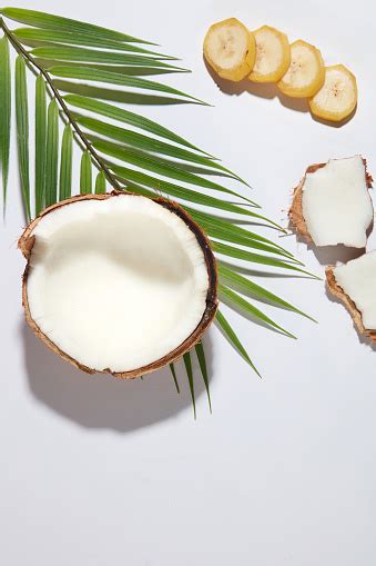 바나나와 코코넛 플랫이 놓인 흰색 평면의 평면도 사진 바나나 조각이 말린 코코넛 조각 옆에 일렬로 배열되어 있고 코코넛 잎 가지가 장식된 빈 공간입니다 0명에 대한 스톡