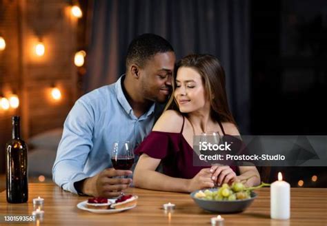 Passionate Interracial Couple Having Romantic Dinner At Home Drinking