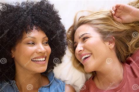 Overhead Close Up Shot Of Loving Same Sex Female Couple Lying On Bed At