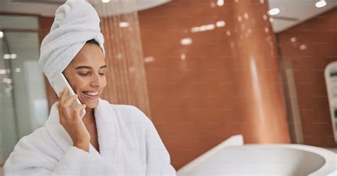 흰색 목욕 가운을 입은 아름다운 아가씨가 스파 살롱에서 욕조 옆에 서서 전화 통화를 하고 웃고 있다 사진 Unsplash의 통신 이미지