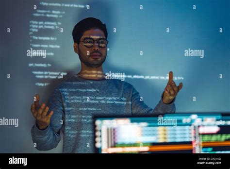 Indian Man Programmer Standing In Front Of A Screen With Code Projected