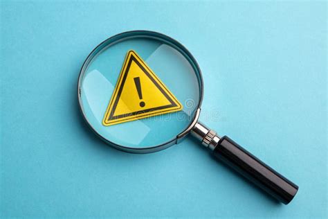 A Yellow Warning Triangle Inside The Glass Of A Magnifying Glass Against A Blue Background With