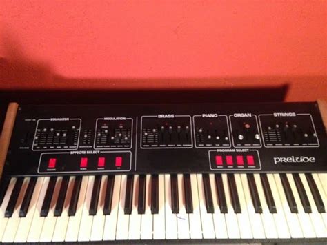 An Electronic Keyboard Sitting On Top Of A Wooden Table Next To A Red