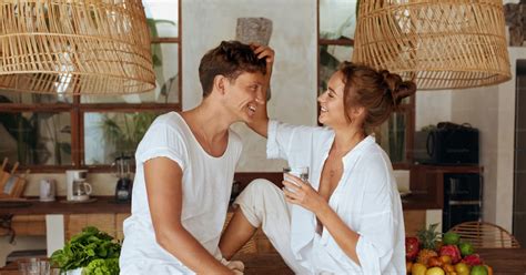 건강한 식단 순수한 물을 마시는 커플 낭만적인 남자는 열대 빌라의 부엌에서 머리를 만지고 유리잔을 들고 여자를 껴안는다