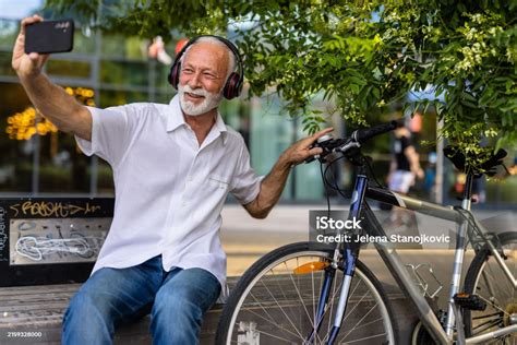 잘생긴 중년 남자가 자전거를 타고 시내에 가서 옆에 서서 스마트 폰으로 셀카를 찍습니다 60 69세에 대한 스톡 사진 및 기타 이미지 60 69세 70 79세