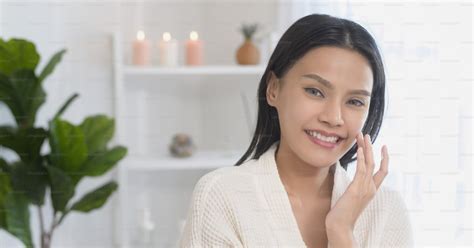 흰 목욕 가운을 입은 행복한 아름다운 여자가 얼굴에 보습 크림을 바르고 있다 사진 Unsplash의 의료 및 의학 이미지