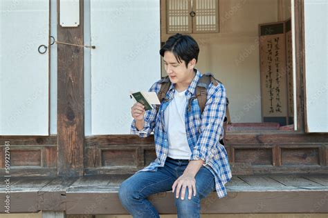 Fotografia Do Stock 한국의 옛날 전통 가옥 마루에 걸터 앉아서 여권 과 항공권을 바라보고 있는 아시아 한국 남자 모델 Adobe Stock
