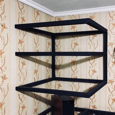 a black shelf sitting in the corner of a room next to a wallpapered wall