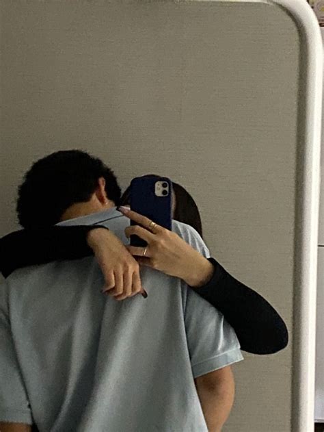 Two People Are Hugging Each Other In Front Of A Mirror And One Person