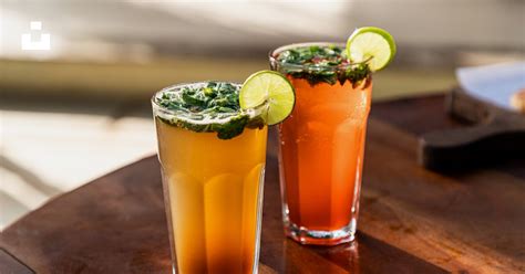 갈색 액체와 갈색 나무 테이블에 얇게 썬 레몬이 있는 투명한 음료수 유리 사진 Unsplash의 무료 마시다 이미지