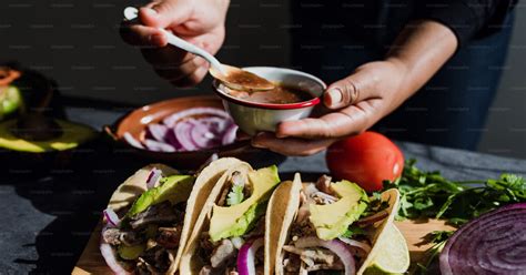 멕시코에서 돼지고기 카르니타 아보카도 양파 고수 빨간 소스를 곁들인 멕시코 타코를 준비하는 라틴 여성 손 사진 Unsplash의 타코 이미지