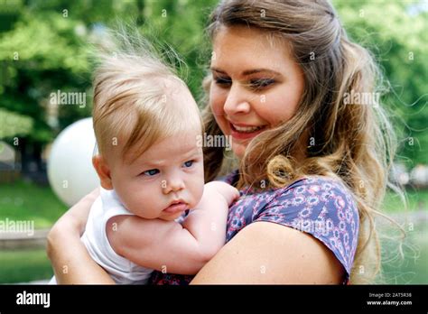 Pretty Blond Mom And Newborn Son In Her Arms In The Park Stock Photo