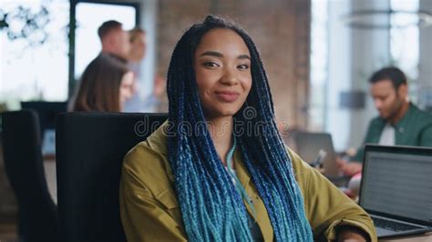 Trendy Girl Manager Posing In Office With Working Team At Backdrop