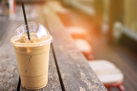 나무 테이블에 테이크 아웃 컵 라 떼 커피 얼음 나무 테이블에 짚으로 플라스틱 컵에 테이크 아웃 아이스 라 떼 나무 테이블에 아이스 라 떼와 카페가 게 배경 0명에 대한