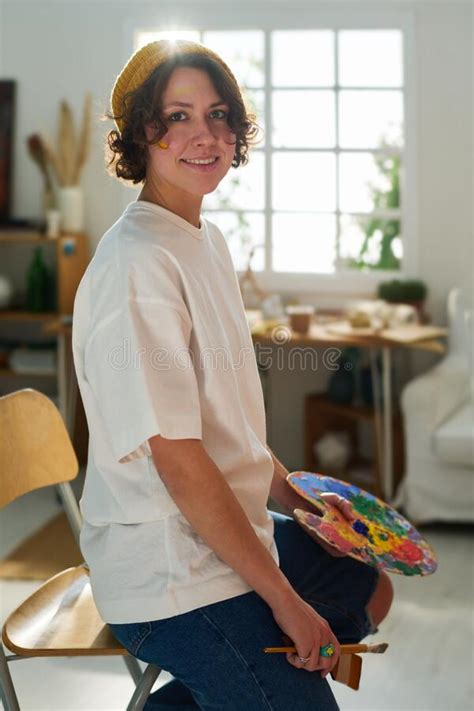 Young Smiling Craftswoman In White T Shirt Sitting In Front Of Camera