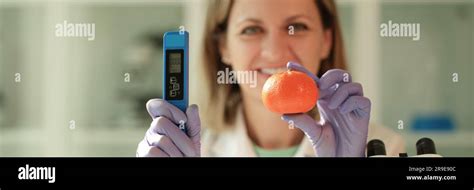 Scientist Chemist Holding In Hands Tangerine And Device For Measuring Amount Of Nitrates In