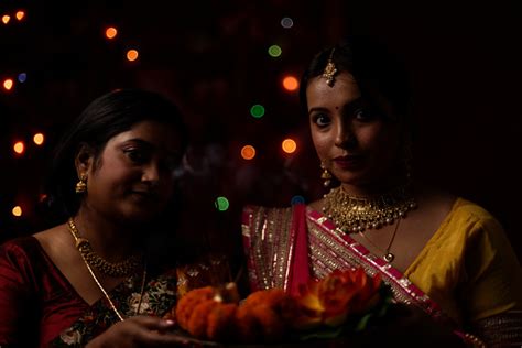 인도 전통 드레스를 입은 두 명의 아름다운 인도 벵골 여성들이 디왈리 의 저녁에 어둠 속에서 실내에서 꽃을 숭배합니다 2명에