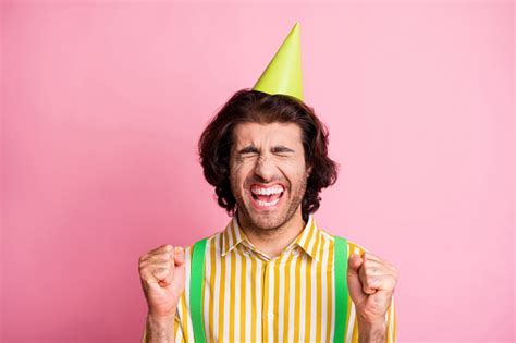 젊은 흥분 다민족 남자의 사진 미친 기뻐 주먹 손 승리 파스텔 색상 배경 위에 고립 된 파티 모자를 착용 갈색 머리에 대한 스톡