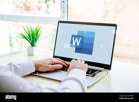 Man Using A Laptop Computer Displaying Logo Of Microsoft Word On The
