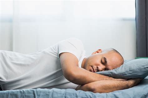 흰색 티셔츠를 입은 30세 무렵의 아시아 대머리 남자가 파란색 매트리스와 베개 위에서 옆에서 자고 있습니다 그는 아침까지 집에서 잤다 코골기에 대한 스톡 사진 및 기타