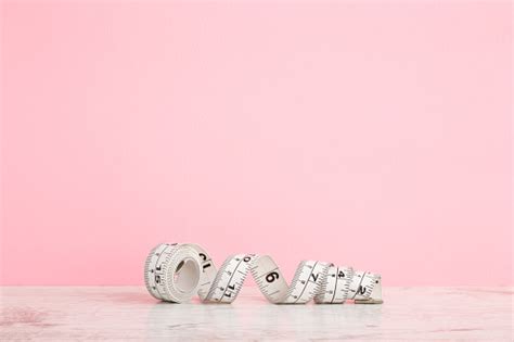 밝은 분홍색 테이블 배경의 나무 테이블에 흰색 측정 테이프 파스텔 색상 근접 촬영 전면 보기입니다 텍스트의 빈 장소입니다 0명에