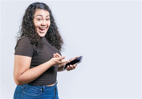 Mujer joven sonriente sosteniendo el teléfono celular y mirando a la cámara feliz chica latina