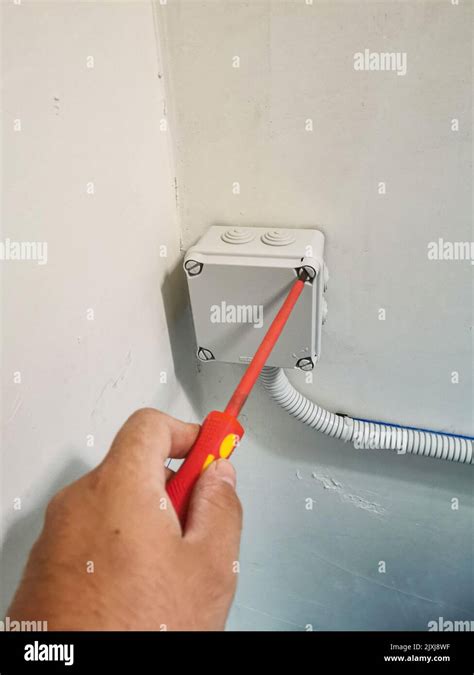A Person Opening A White Sealed Electrical Box With A Red Flathead Screwdriver Stock Photo Alamy