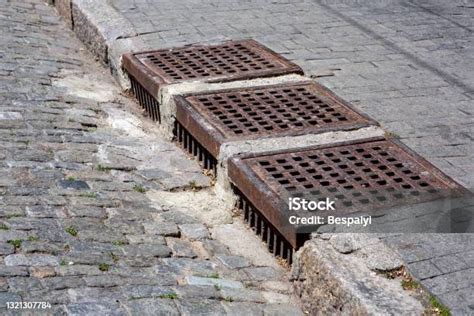 화창한 날에는 포장석에서 도로 근처의 화강암 타일에서 보도의 빗물 시스템의 맨홀 그릴의 철 격자가있는 도시 인프라의 배수 시스템 아무도 없습니다 Runoff Election