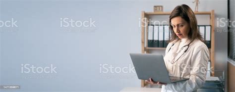 의료 작업 공간 사무실에 서 있는 동안 노트북 컴퓨터로 작업하는 의사 의료 정보를 검색합니다 기치 40 44세에 대한 스톡 사진 및 기타 이미지 Istock
