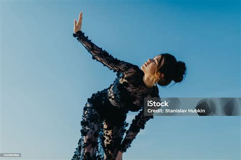 레이스 블랙 드레스를 입은 여성이 푸른 하늘을 배경으로 서 있다 20 29세에 대한 스톡 사진 및 기타 이미지 20 29세 가냘픈 가리기 Istock