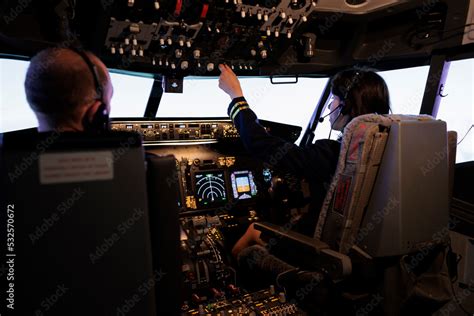 Female Pilot Assisting Captain To Takeoff And Fly Airplane Using Buttons On Dashboard Command