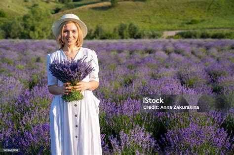 모자를 쓴 흰색 드레스 의상을 입은 여성 모델의 초상화 그녀는 라벤더 필드 사진 세션에서 서서 웃고 있습니다 어린 소녀가 라벤더 꽃다발을 들고 있습니다 행복과 자유 30