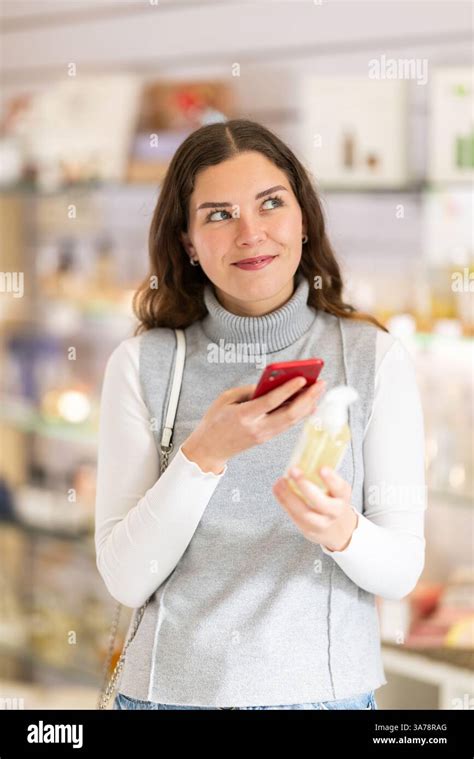 Female Shopper Scanning QR Code On Perfume In Perfume Shop Stock Photo Alamy