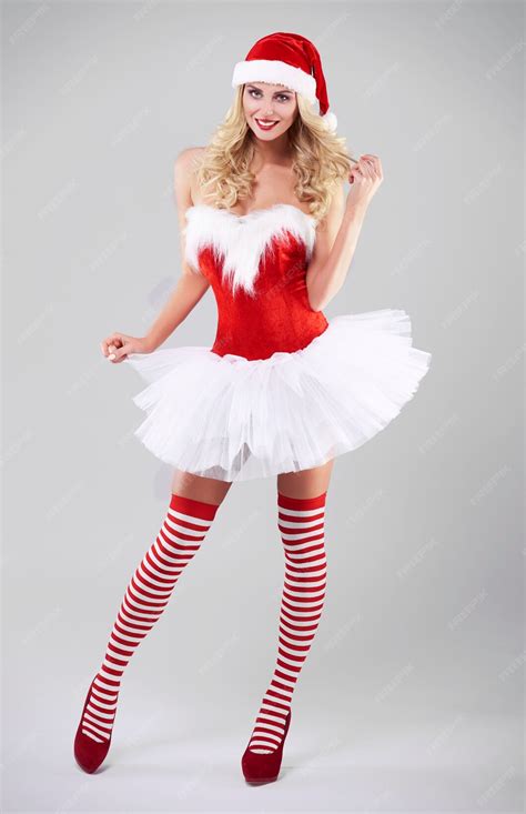 Сексуальная женщина в костюме санта клауса на серой стене Бесплатно Фото