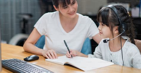 홈스쿨 코로나바이러스 전염병으로 인해 디지털 원격 인터넷 회의를 통해 학교 교사로부터 온라인 수업을 배우는 아시아 어린 소녀 컴퓨터를 보고 메모를 쓰는 아이 어머니와