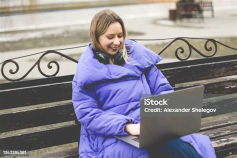 뷰티 패션 여성의 초상화 그녀는 보라색 재킷을 입고 거리의 갈색 벤치에서 작업합니다 따뜻한 음료와 회색 노트북 의 컵 개념 사진 20 24세에 대한 스톡 사진 및 기타