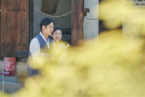 한복을 입고 한국의 전통 가옥 노란꽃 흐린배경 담장을 배경으로 커플 여행자 아름답고 멋진 젊은 아시아 한국 남녀 모델 Stock 写真 Adobe Stock