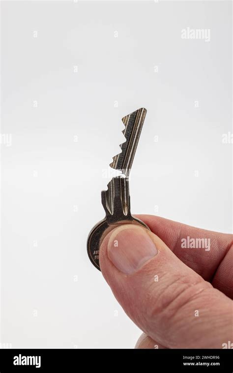 male hand holding an open door key cylinder key white background